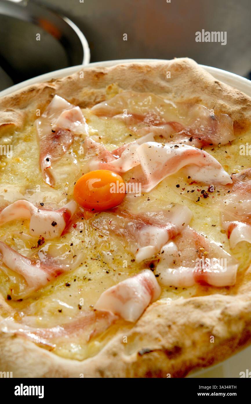 A freshly baked thin crust pizza topped with mozzarella, cured ham, and ...