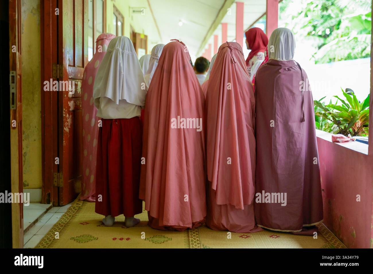 Back view of unrecognizable women, dressed in soft pink and maroon ...