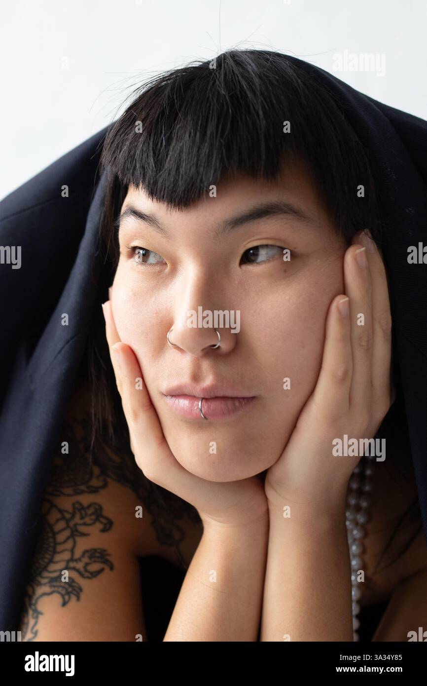 A close-up portrait of a young Asian woman with dark hair, bangs, and facial piercings Stock ...