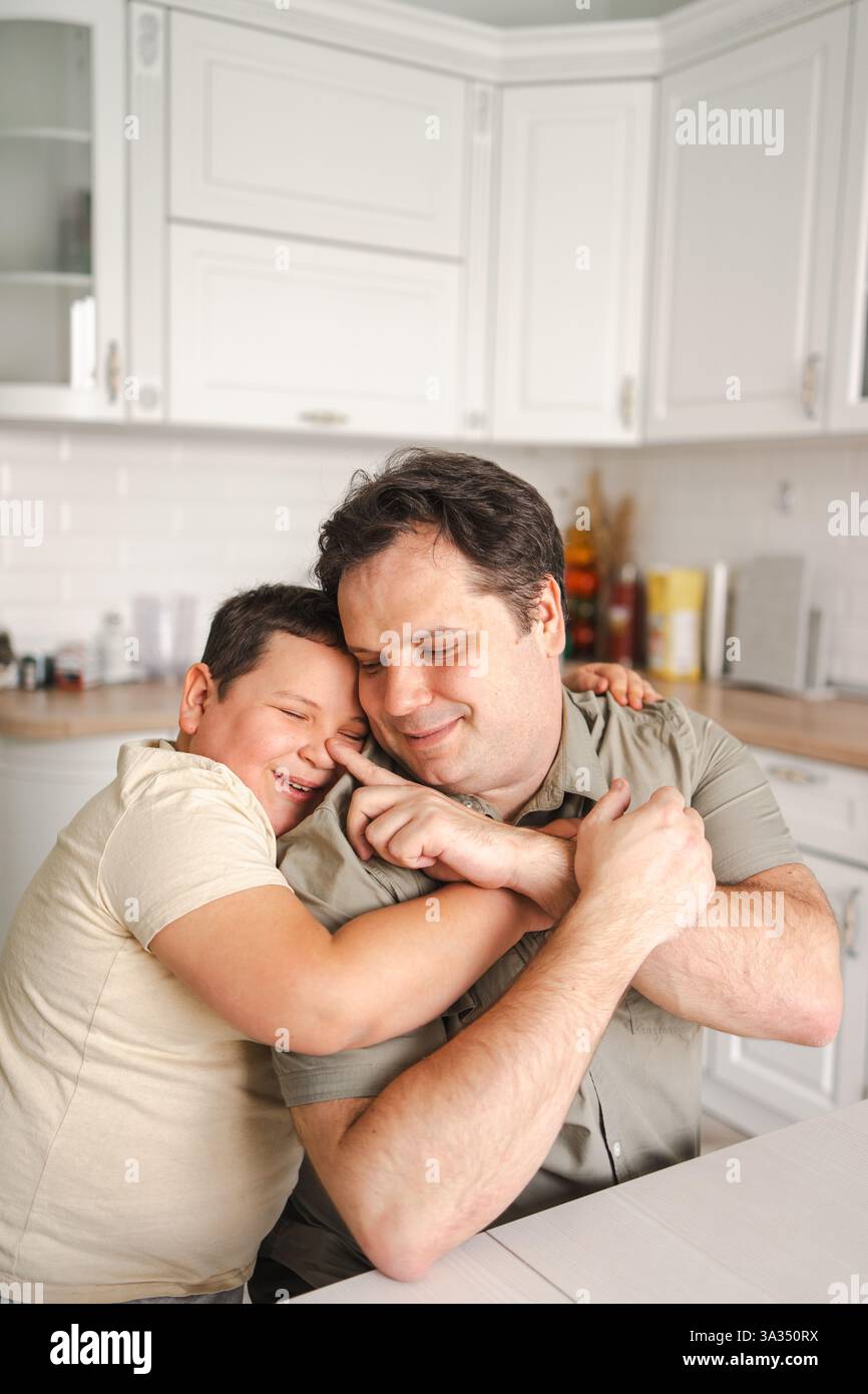 A touching moment as a father and son embrace in a well lit kitchen ...