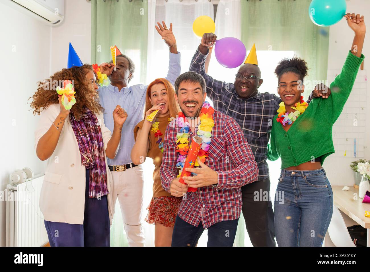 A vibrant group of friends celebrates a birthday indoors. They wear ...