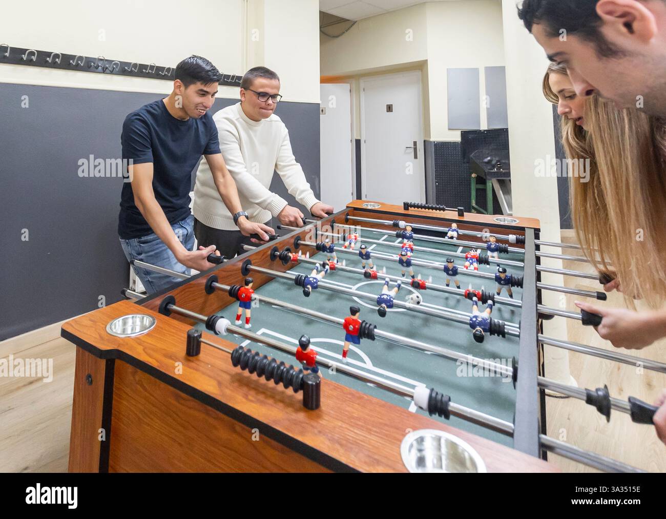 A diverse group takes part in a lively game of table football at a ...