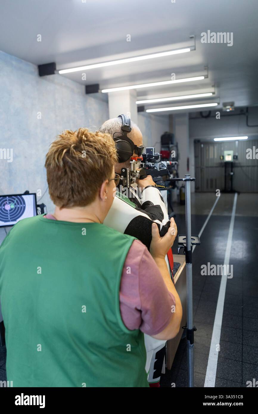 A visually impaired athlete trains at an Olympic shooting range with a ...