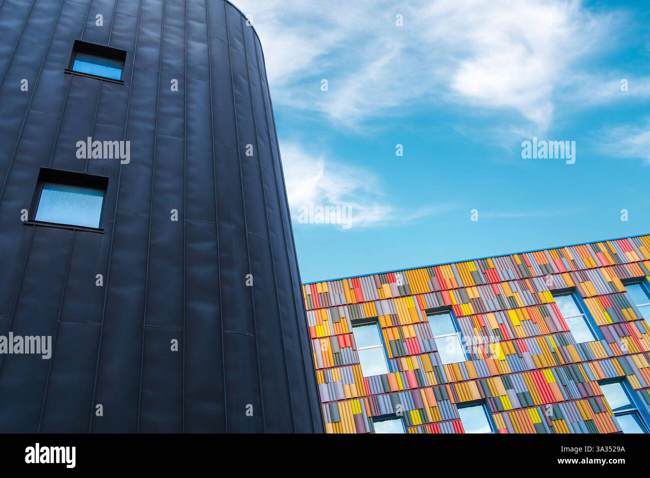 Low angle of a striking architectural contrast between a sleek, dark ...