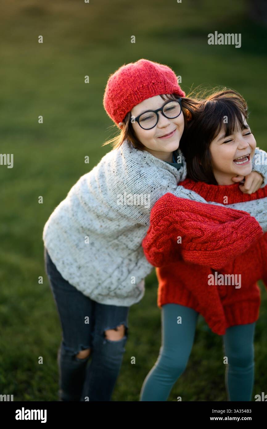 Two joyful siblings, a girl and a boy, embrace warmly during an autumn ...