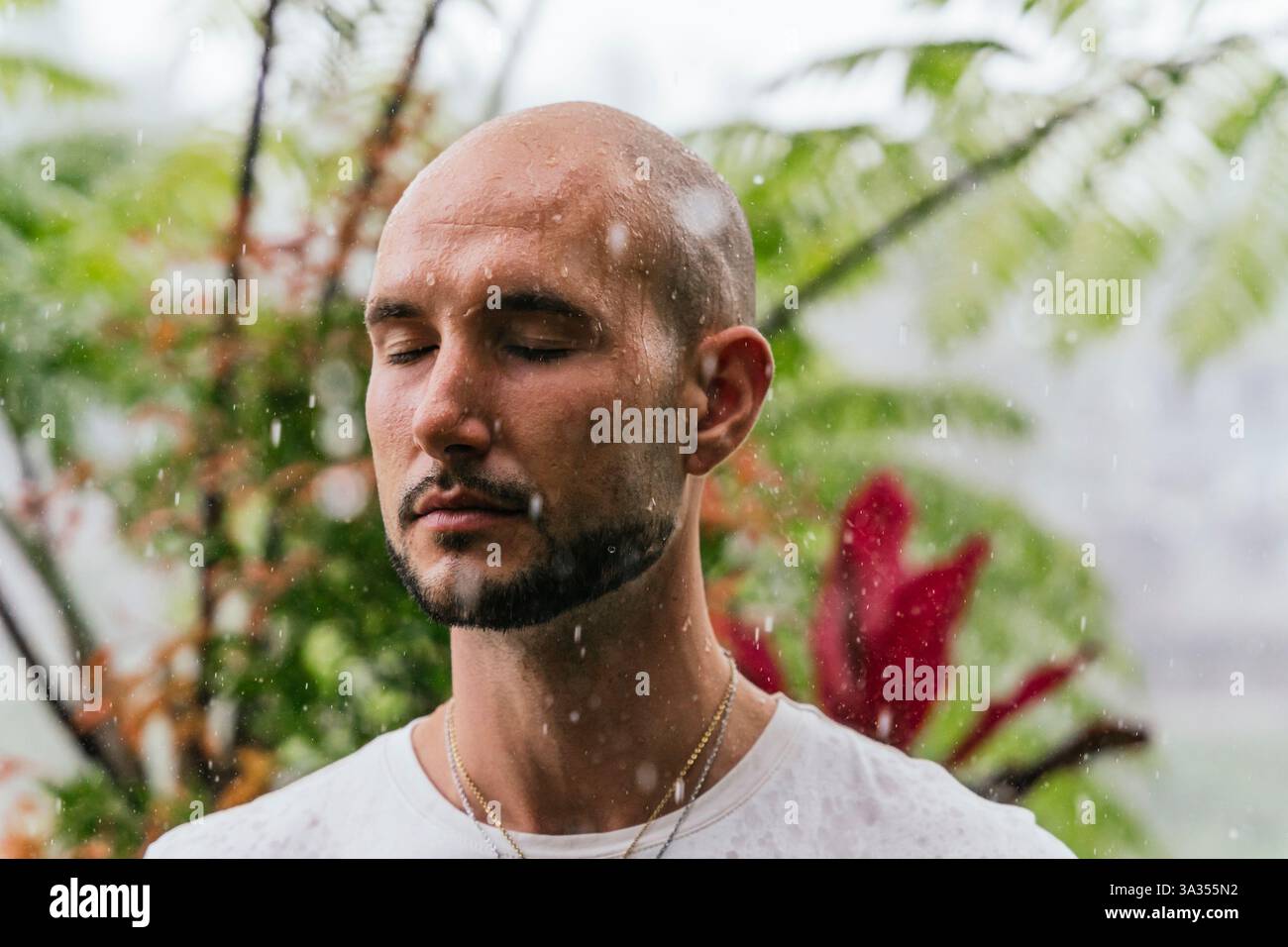A man stands with closed eyes, embracing the gentle rainfall ...
