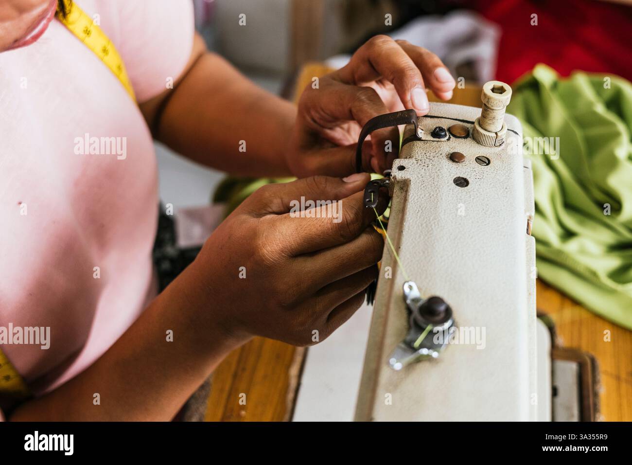Close up of hands asian seamstress adjusting an industrial sewing ...
