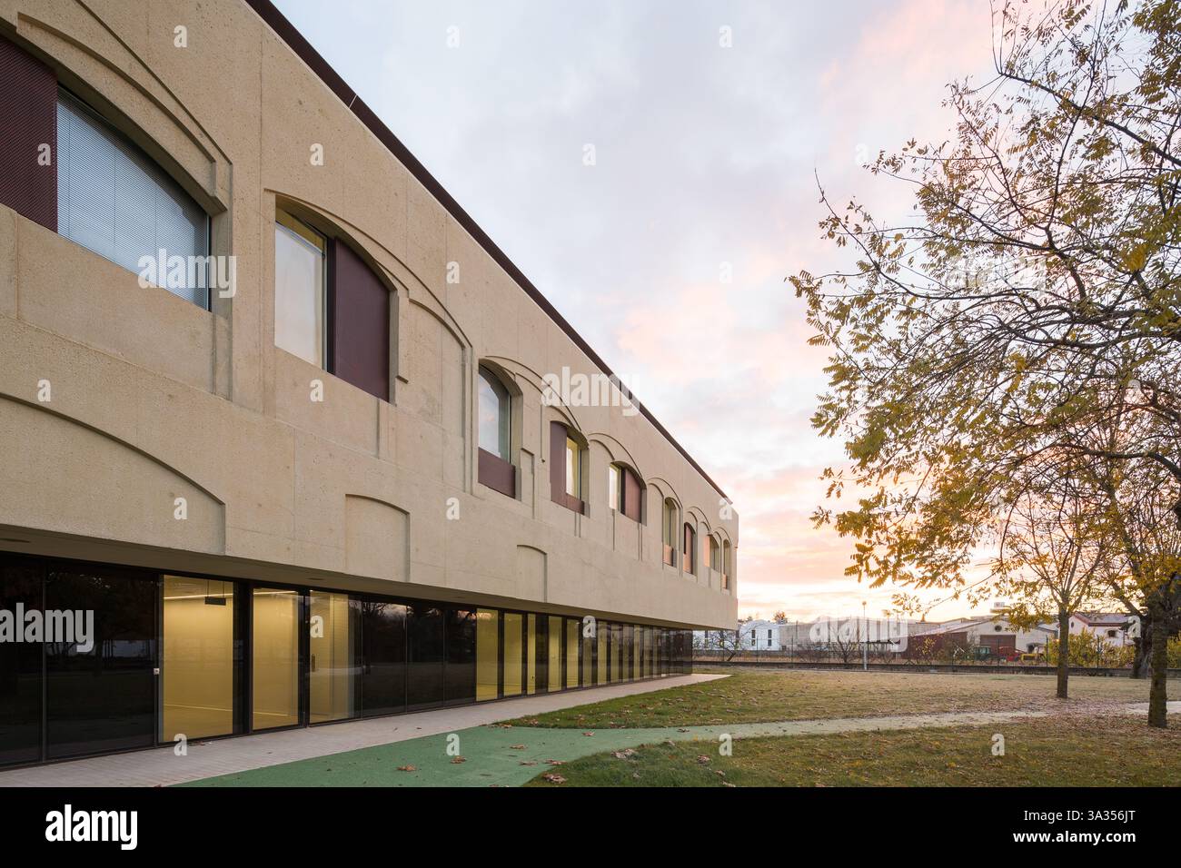 A modern hospital showcases arched windows and beige facade, surrounded ...