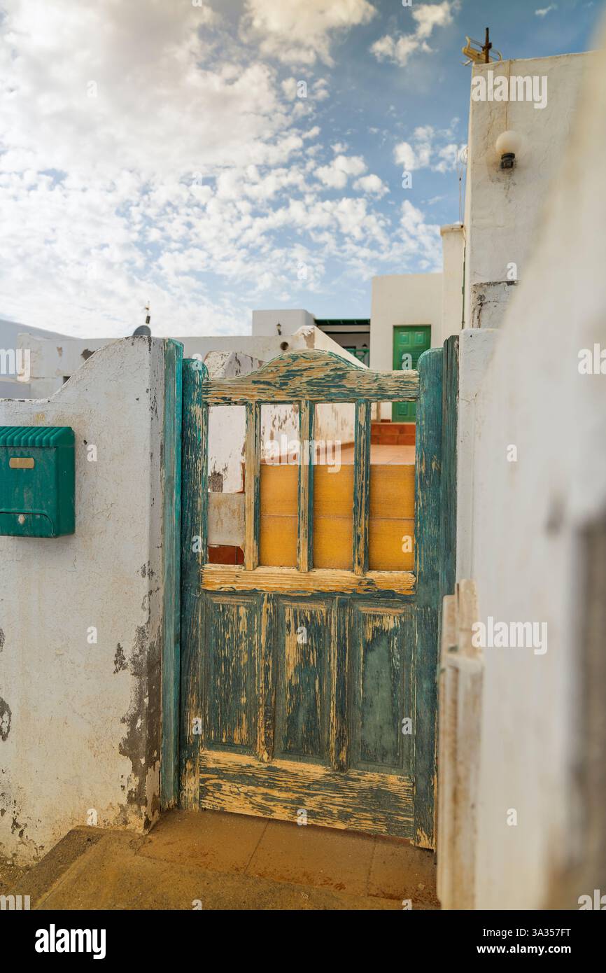 An old, turquoise wooden gate stands open, revealing a peek of a ...