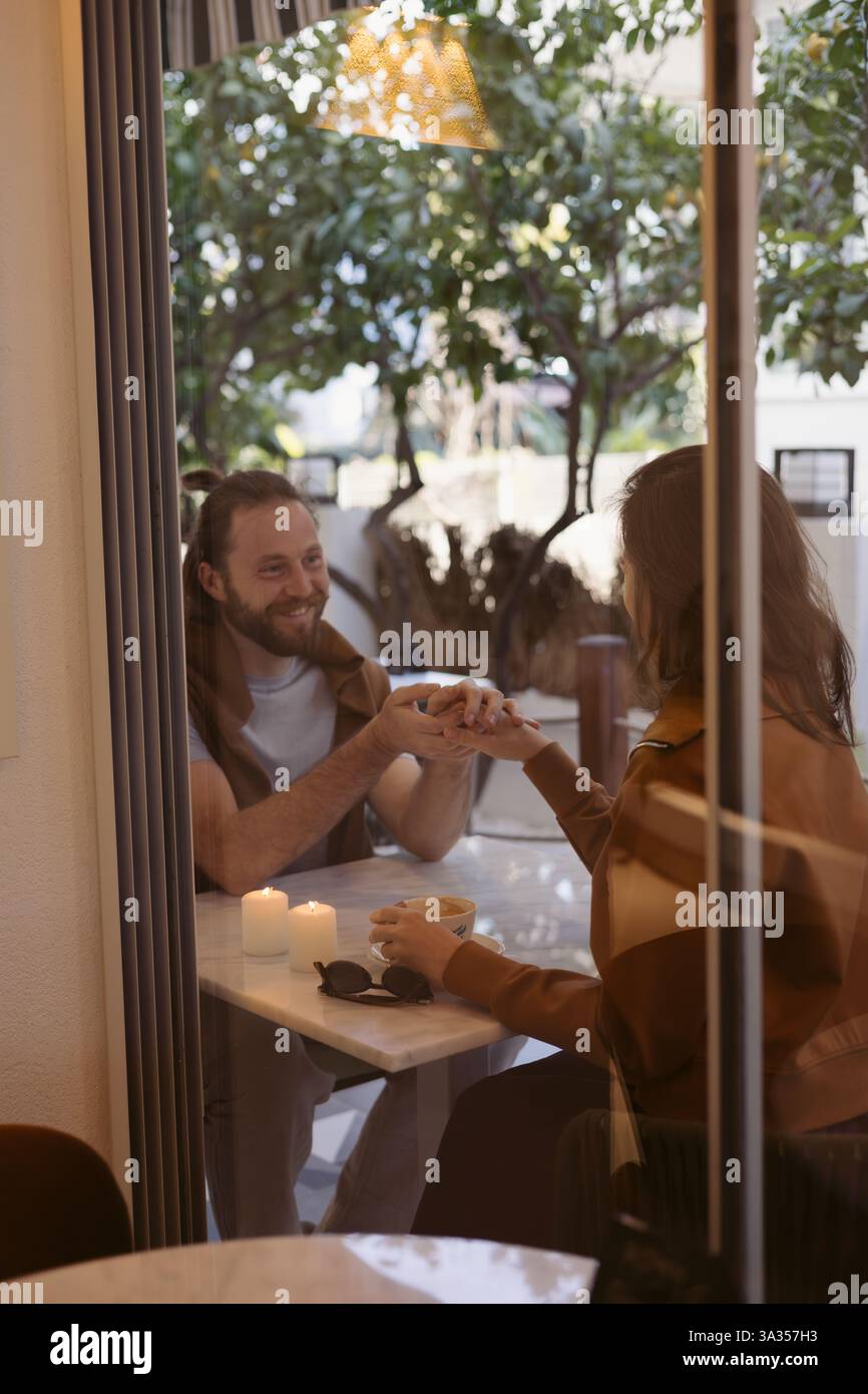 View through cafe window. A man and woman share a warm moment at a cafe ...