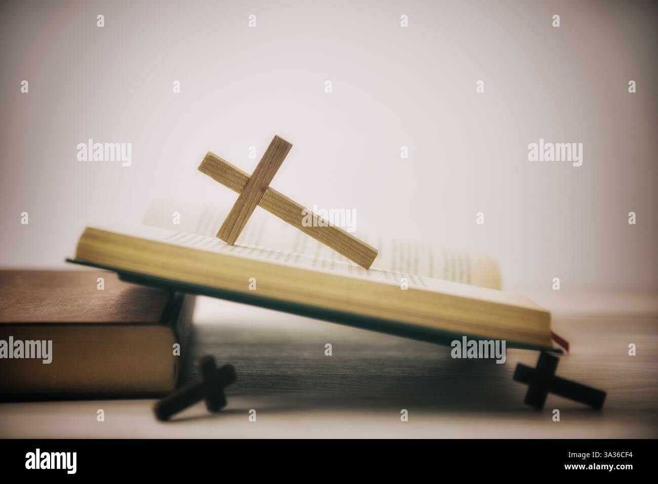 Old open Bible on a wooden table with several wooden crosses and ...