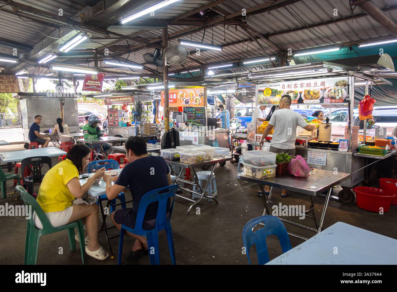 an open-air food street with numerous stalls and seating areas serving ...