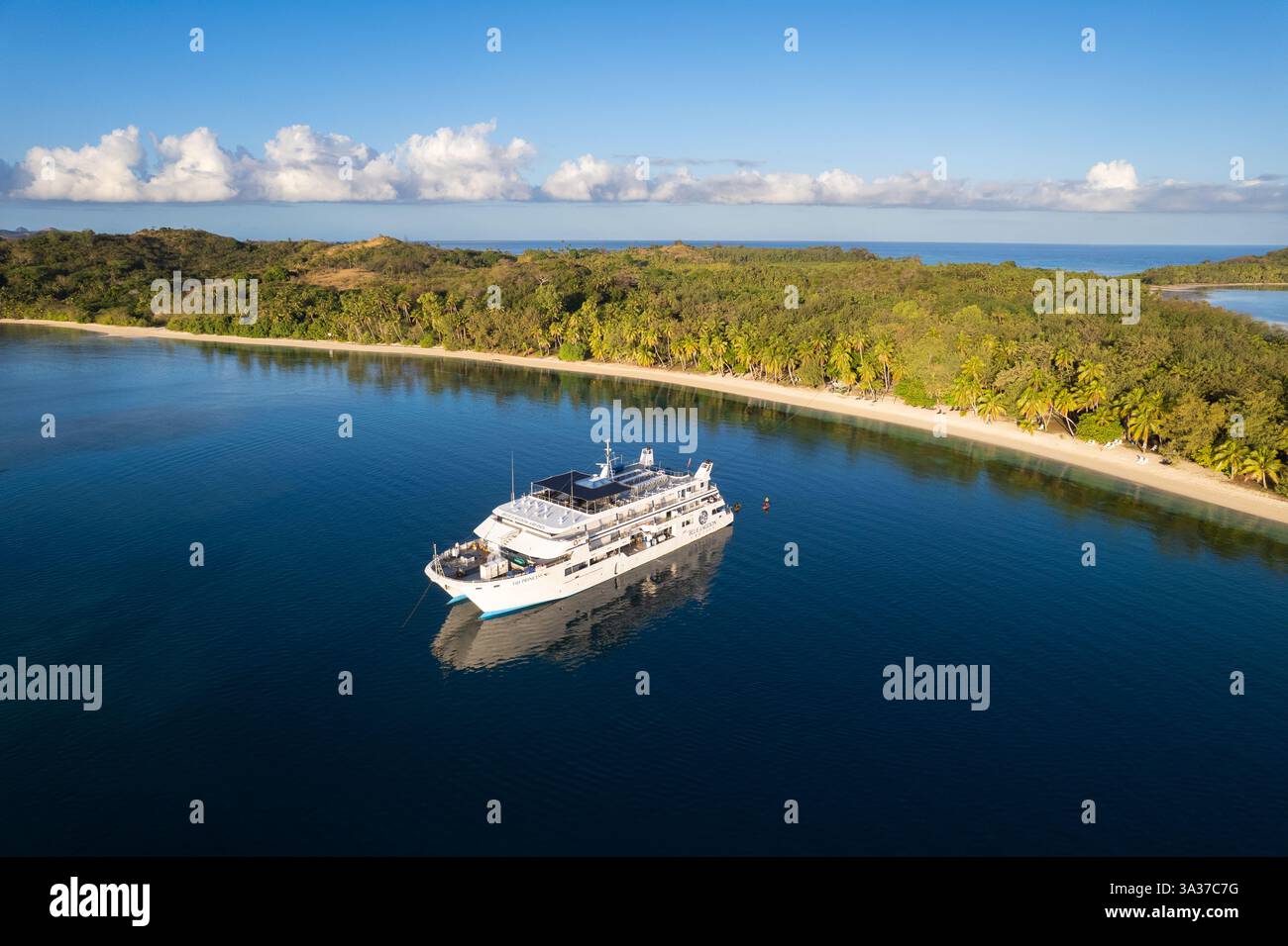 Aerial view of small cruise ship anchored by tropical palm tree ...