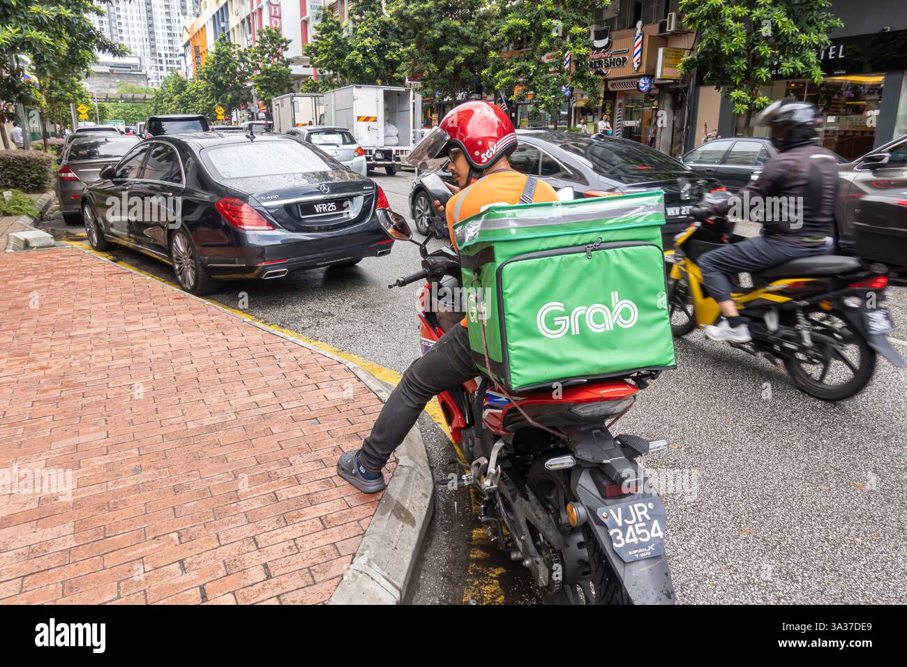 Grab delivery rider on a motorcycle in an urban street, Kuala Lumpur ...