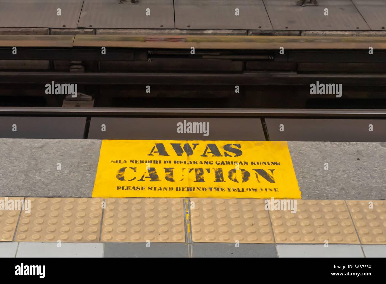 Bilingual warning sign in Malay and English, stay behind the yellow ...