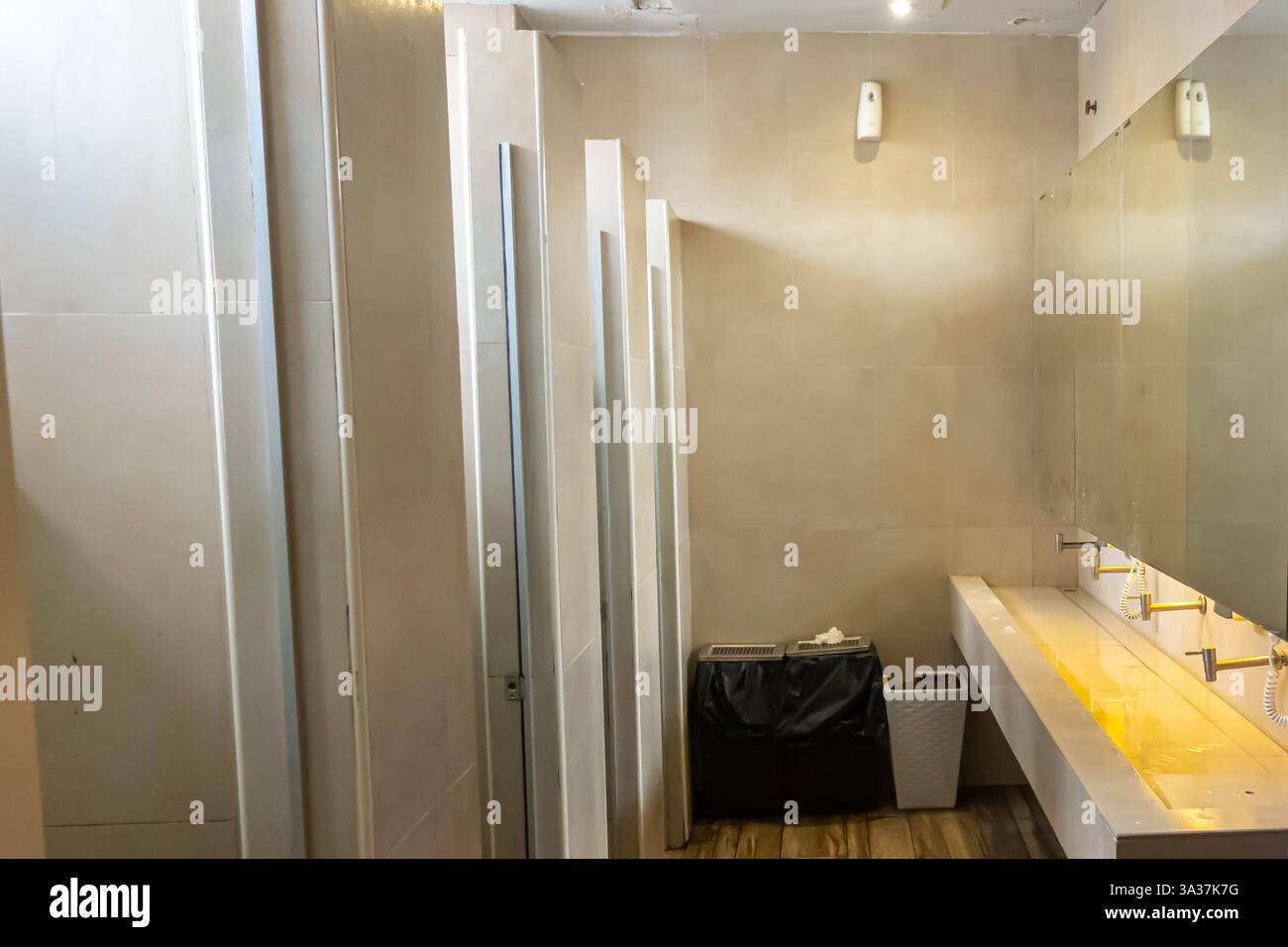 a restroom area, featuring multiple white doors or partitions leaning ...