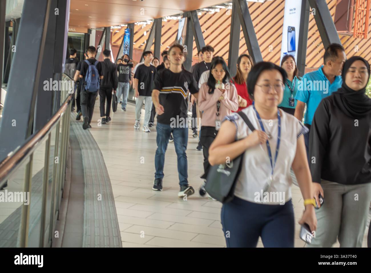 group of people walking on an elevated walkway. modern building or complex, steel beams, Kuala ...