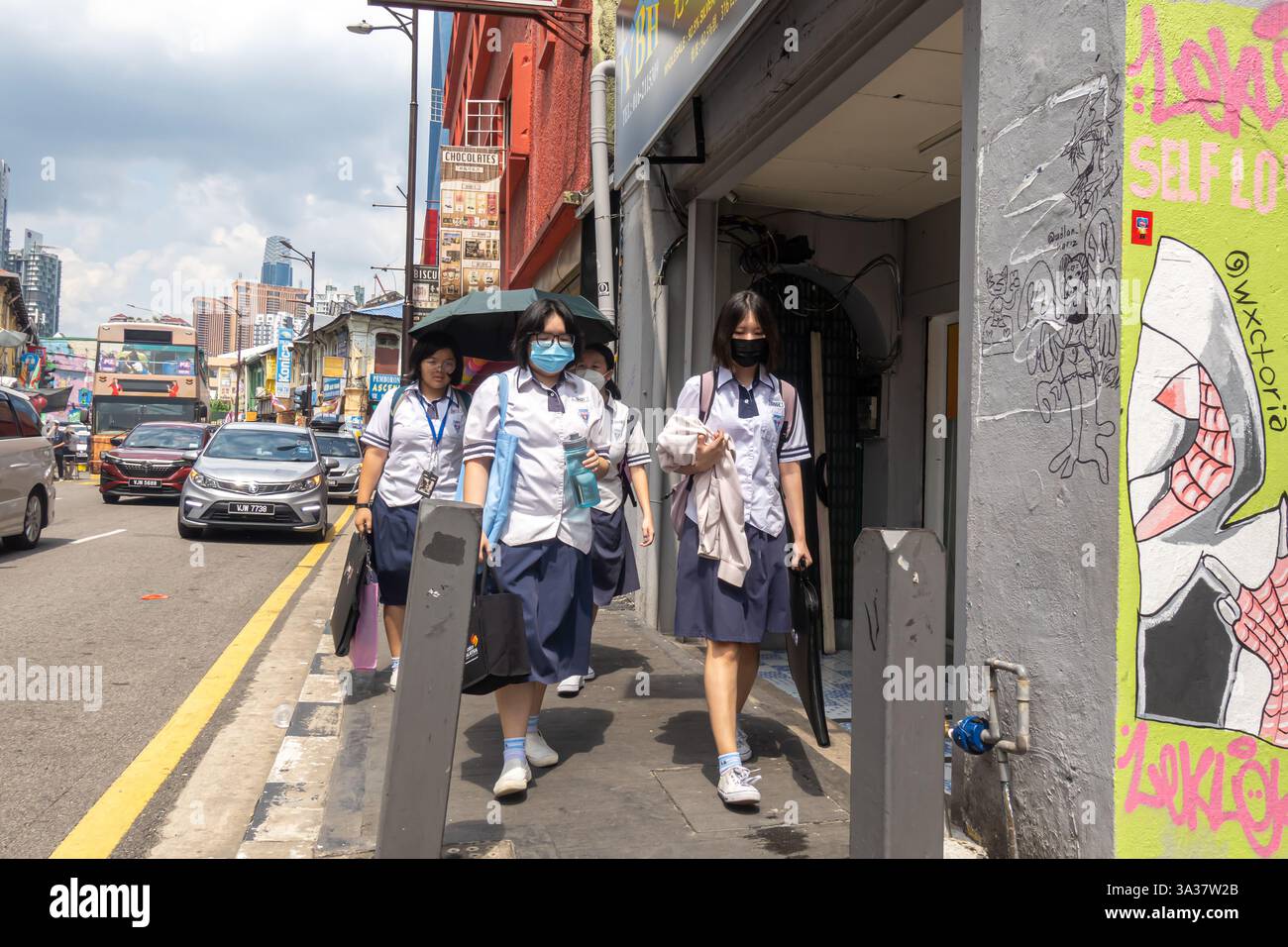 group of female students in school uniforms and face masks walking on a ...