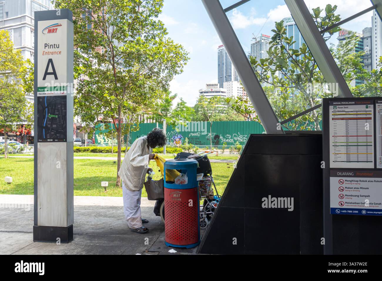 A homeless emptying a trash bin at a public transportation station in ...