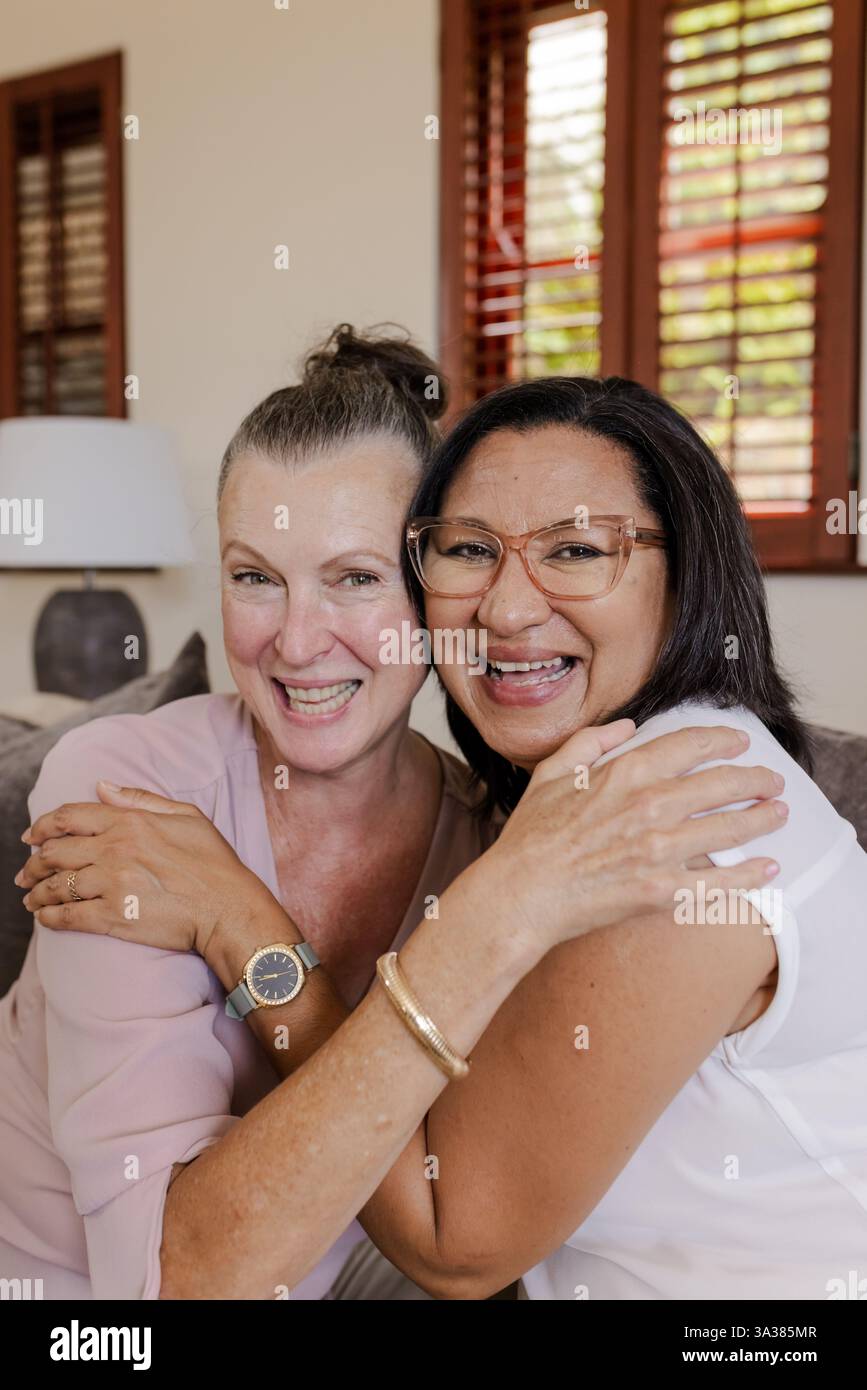 Two senior women embracing and laughing together at home, enjoying ...