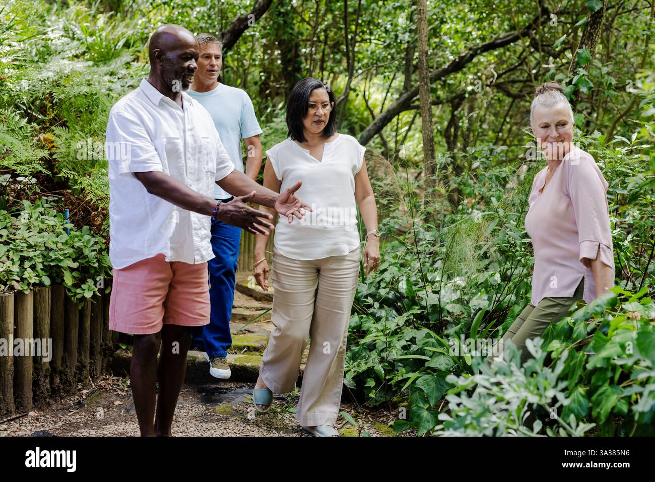 Group of senior friends enjoying nature walk in lush garden, sharing ...