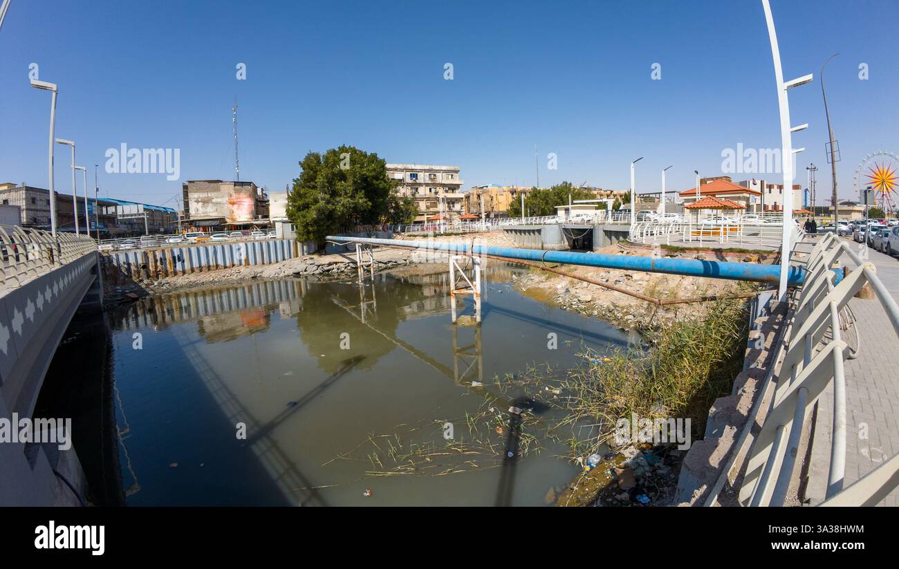 Urban canal with a blue pipeline crossing over, surrounded by buildings ...
