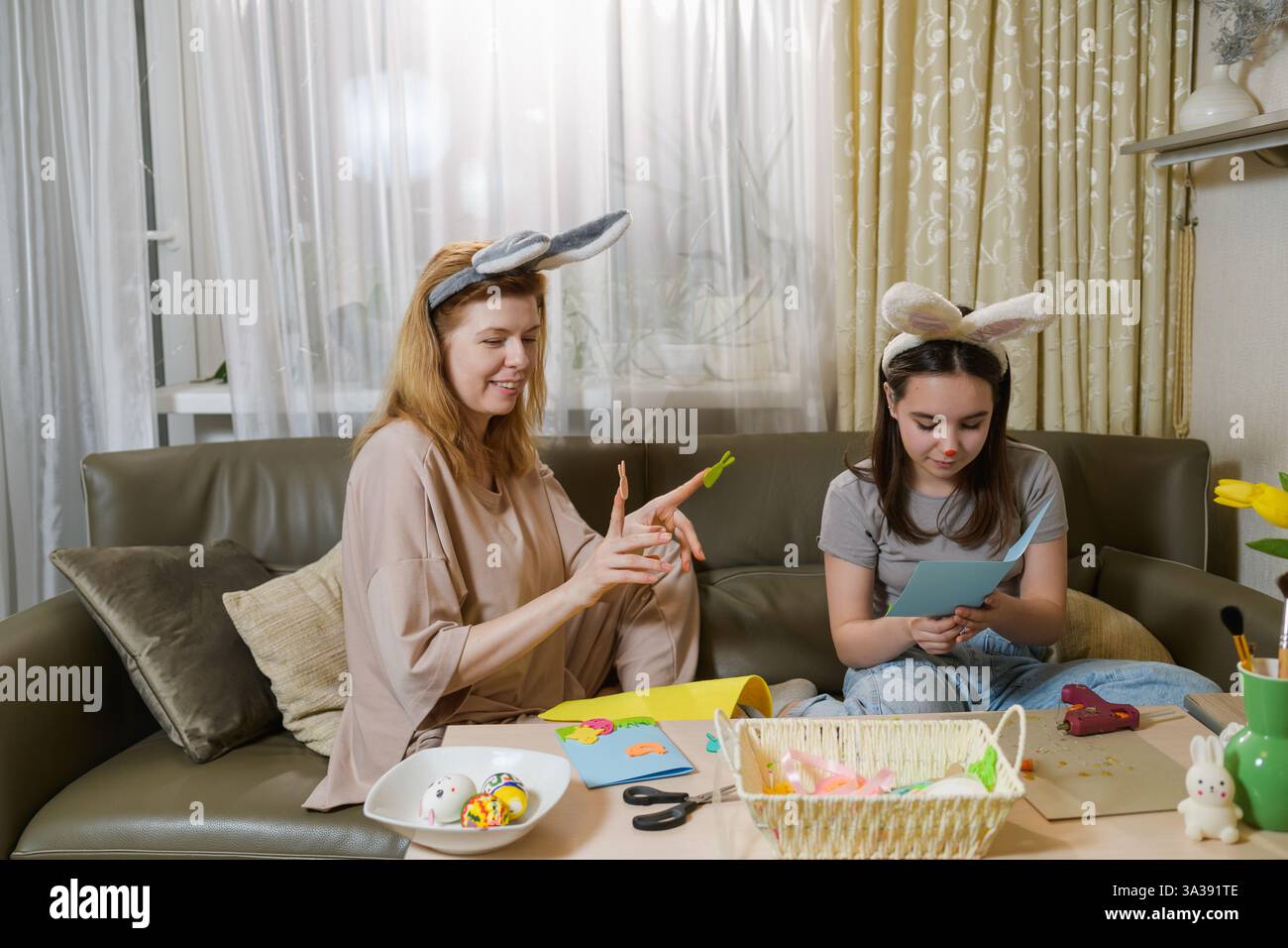 A mother and daughter wearing bunny ears are making Easter crafts at ...