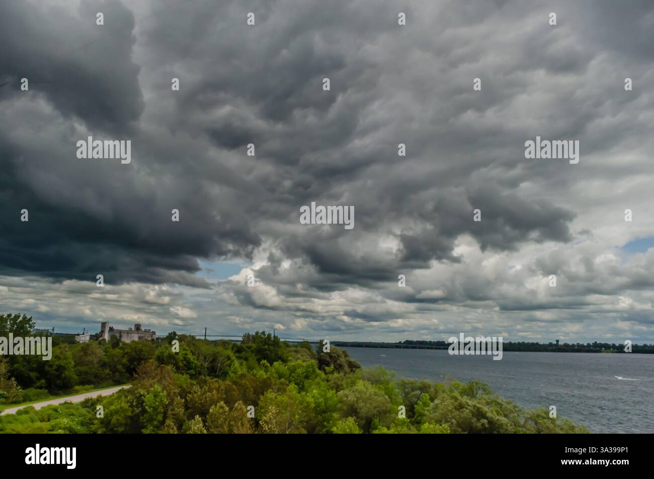 Old concrete grain silo surrounded by a trees with dark clouds overhead ...