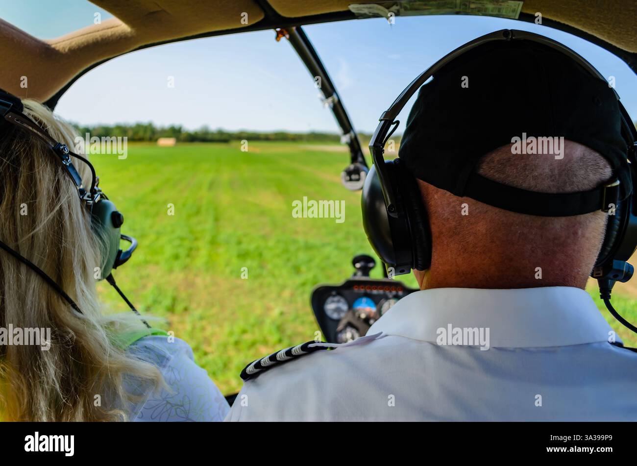 Helicopter interior at low level flightover a field with male pilot and ...