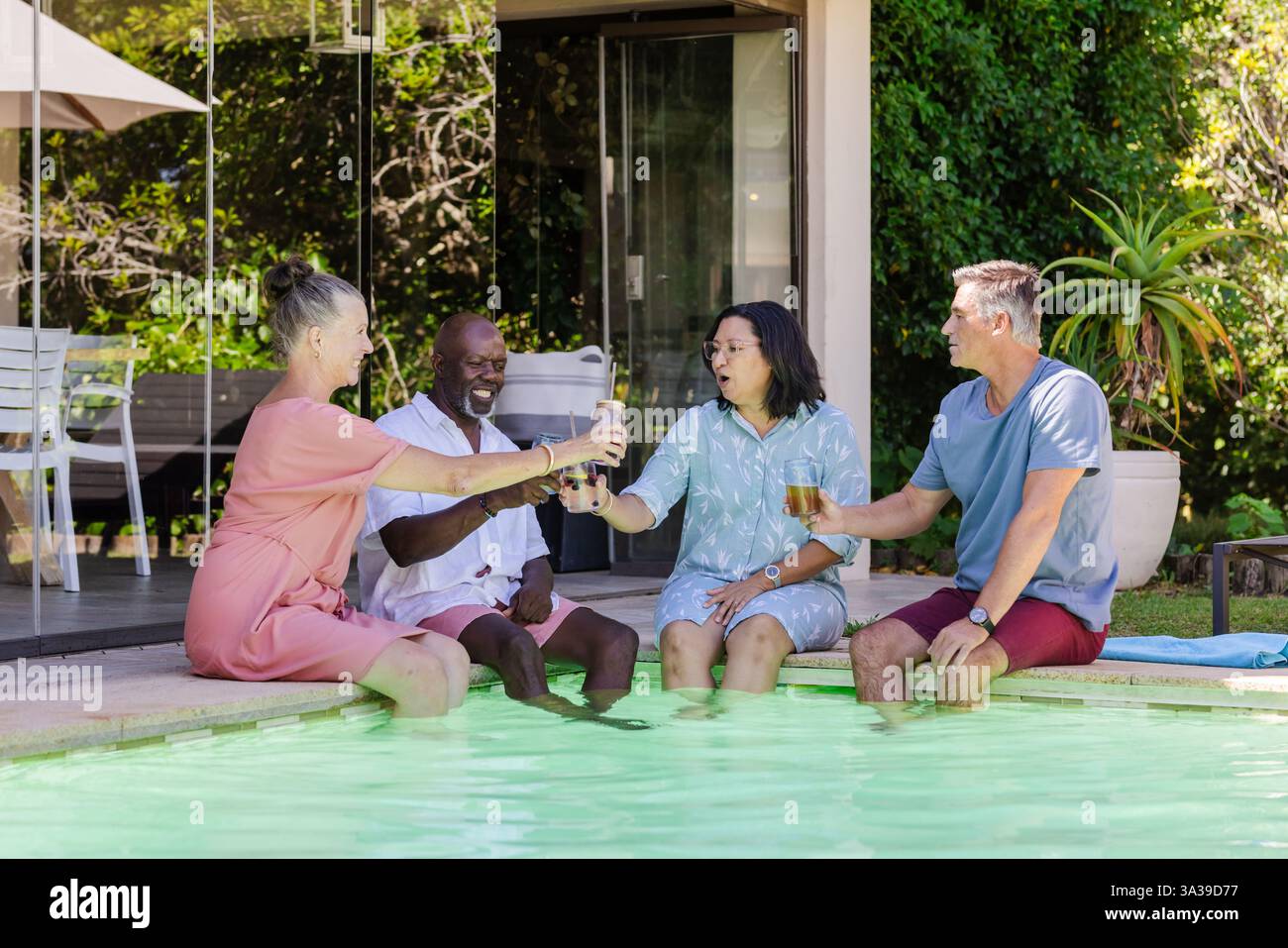 Senior Friends enjoying drinks by poolside, laughing and relaxing in ...