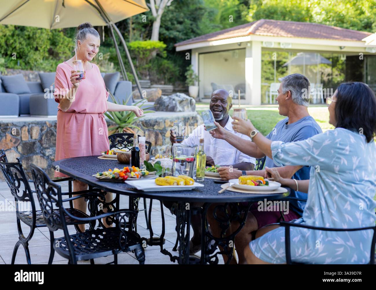 Diverse senior friends enjoying outdoor lunch, raising glasses and ...