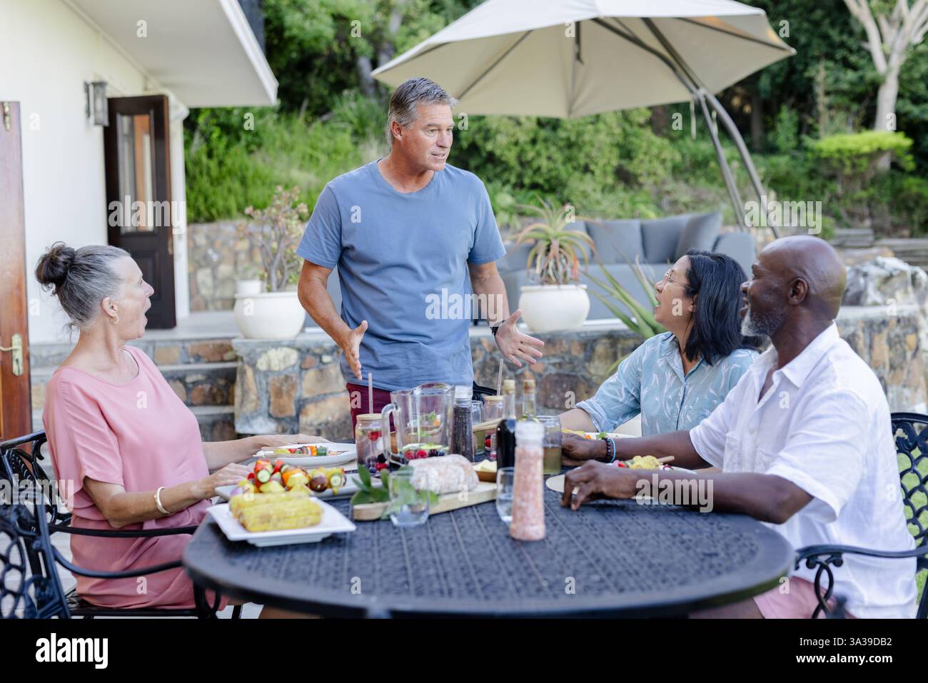 Group of Diverse senior friends enjoying outdoor lunch, smiling and ...