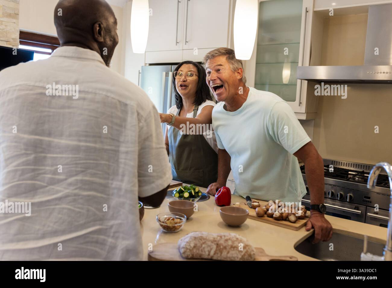Preparing meal, friends laughing together in modern kitchen, sharing ...