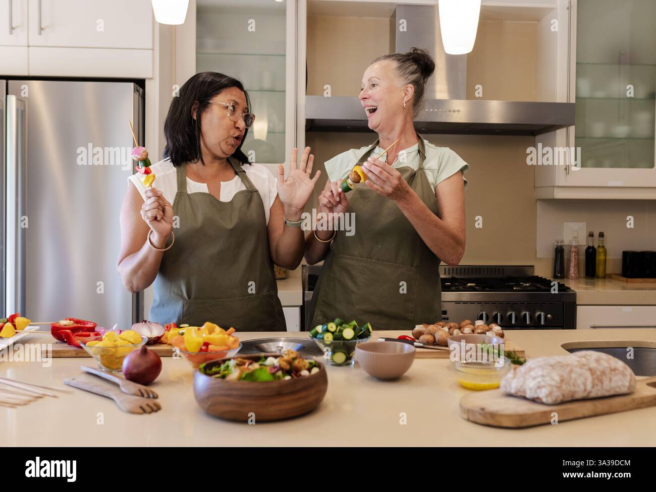 Senior women in kitchen laughing while preparing healthy vegetable ...