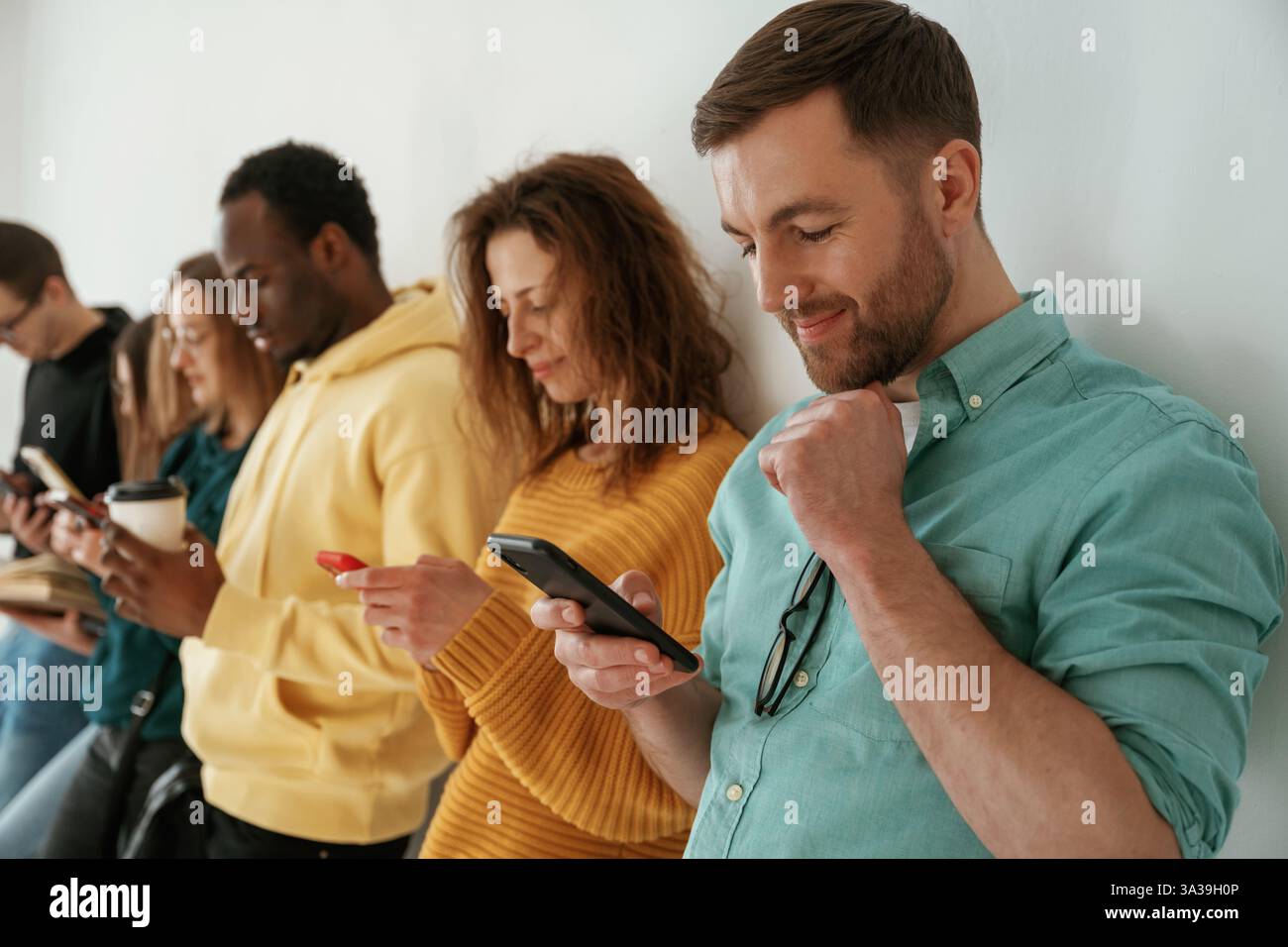 Busy by using smartphones. Group of young people are standing against ...