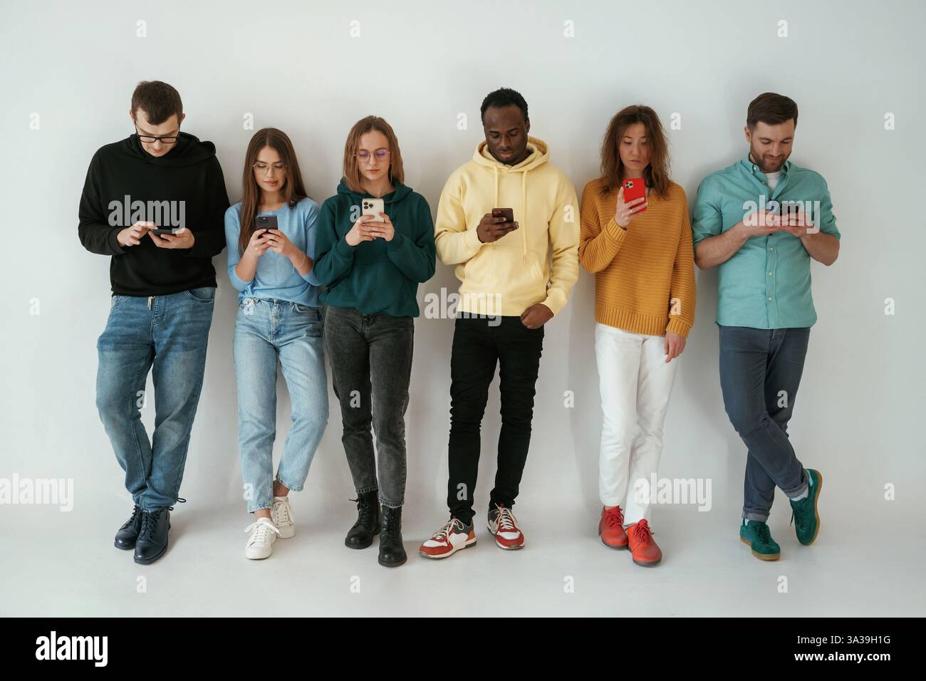 Busy by using smartphones. Group of young people are standing against ...