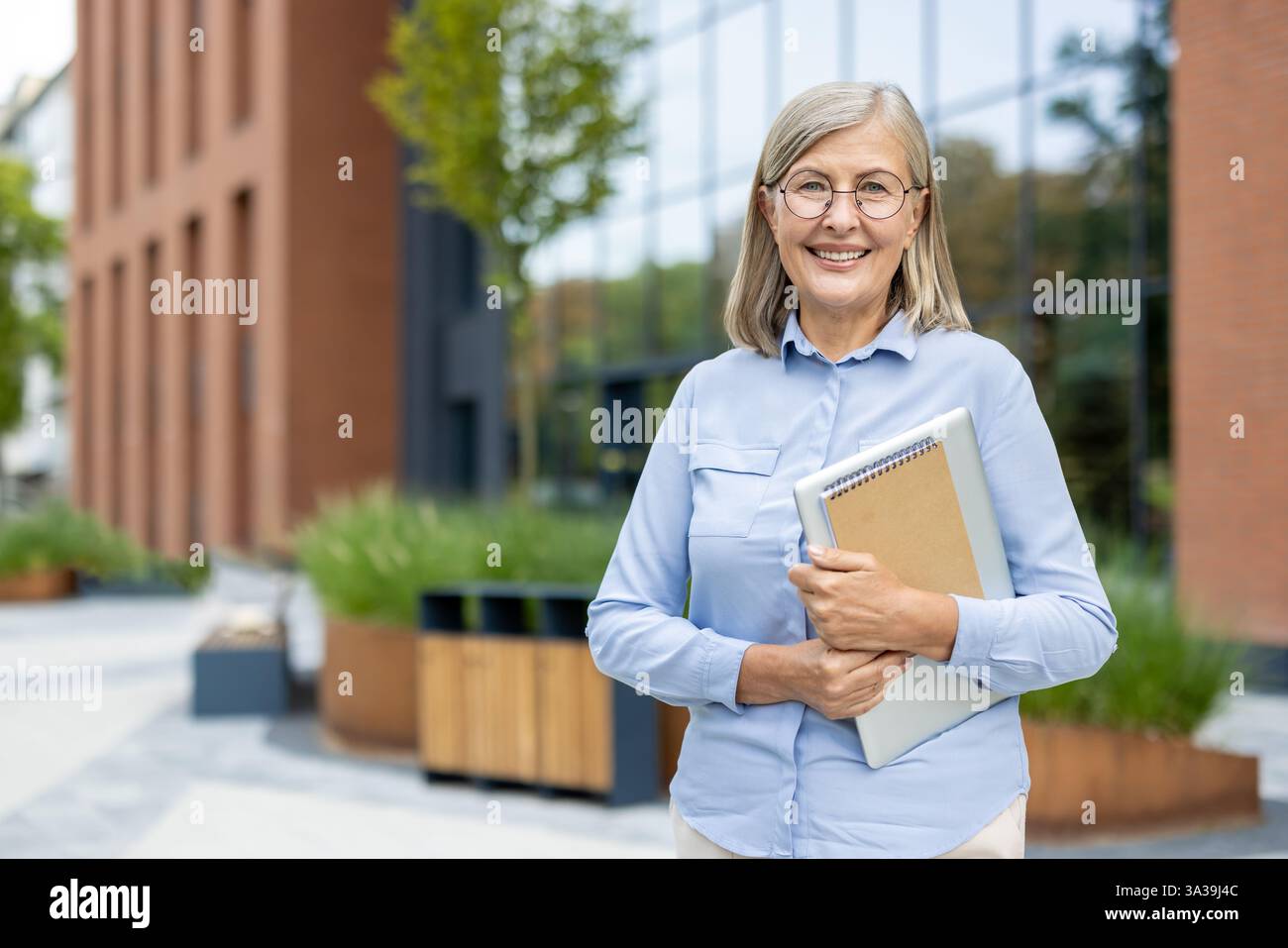 A smiling, mature professional woman stands confidently outside an ...