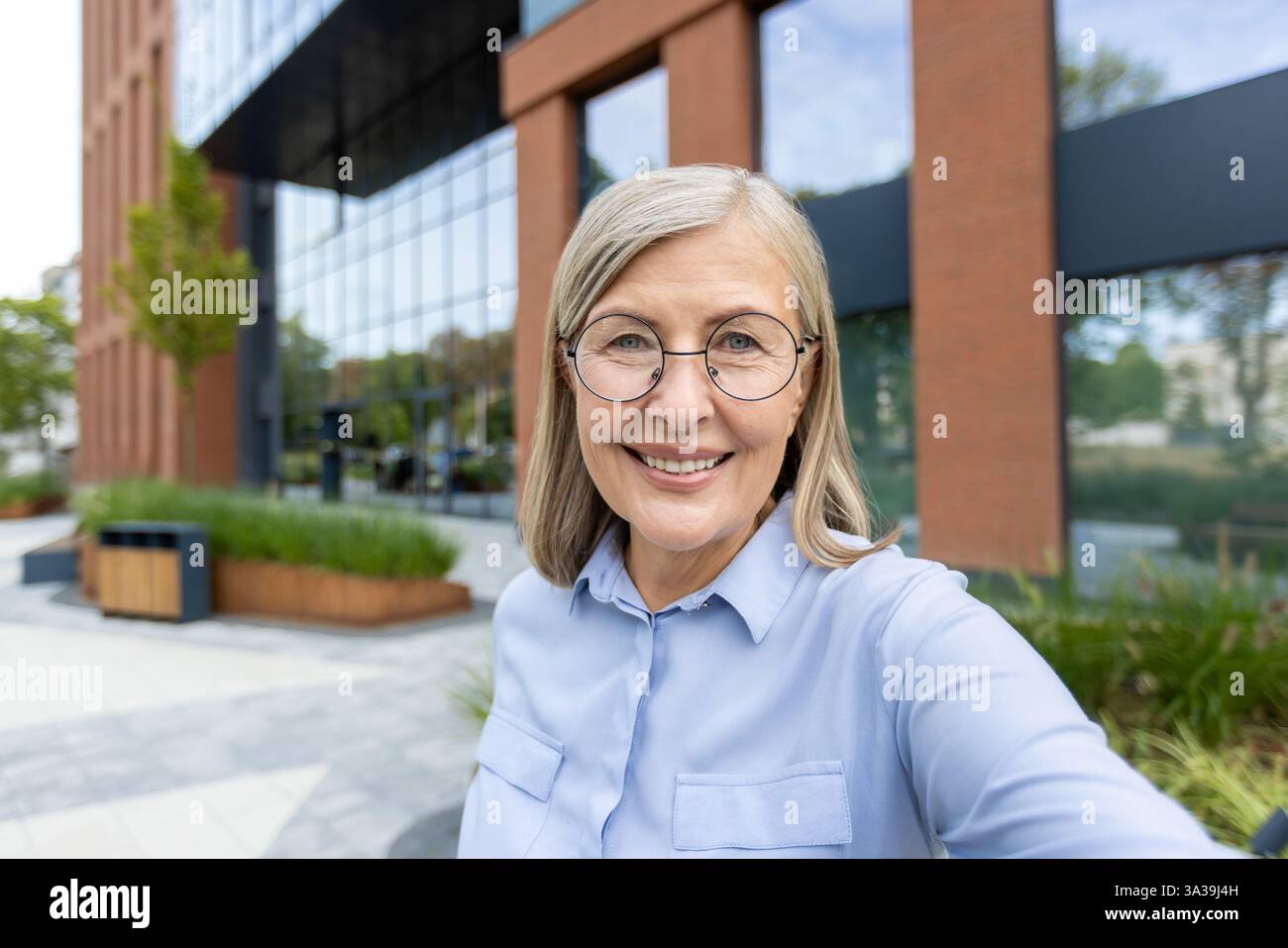 A businesswoman takes a selfie near her office building, capturing her ...