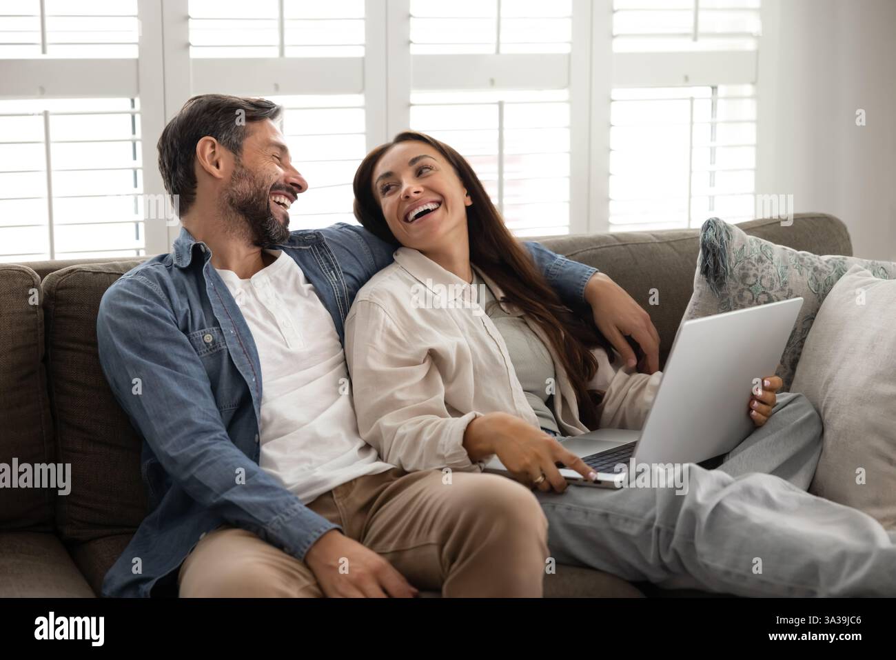 Happy cheerful Latin couple enjoying Internet communication at home ...