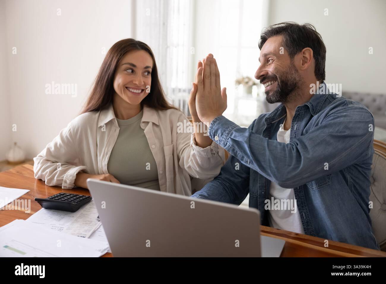 Cheerful excited husband and wife giving high five Stock Photo - Alamy