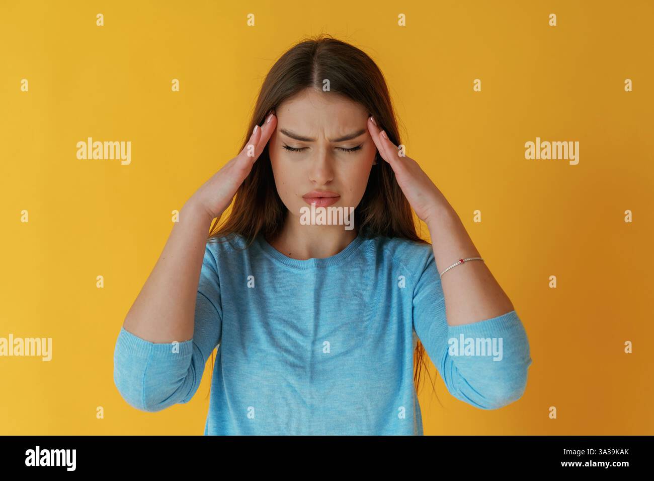 Bad headache. Young woman is against yellow background Stock Photo - Alamy