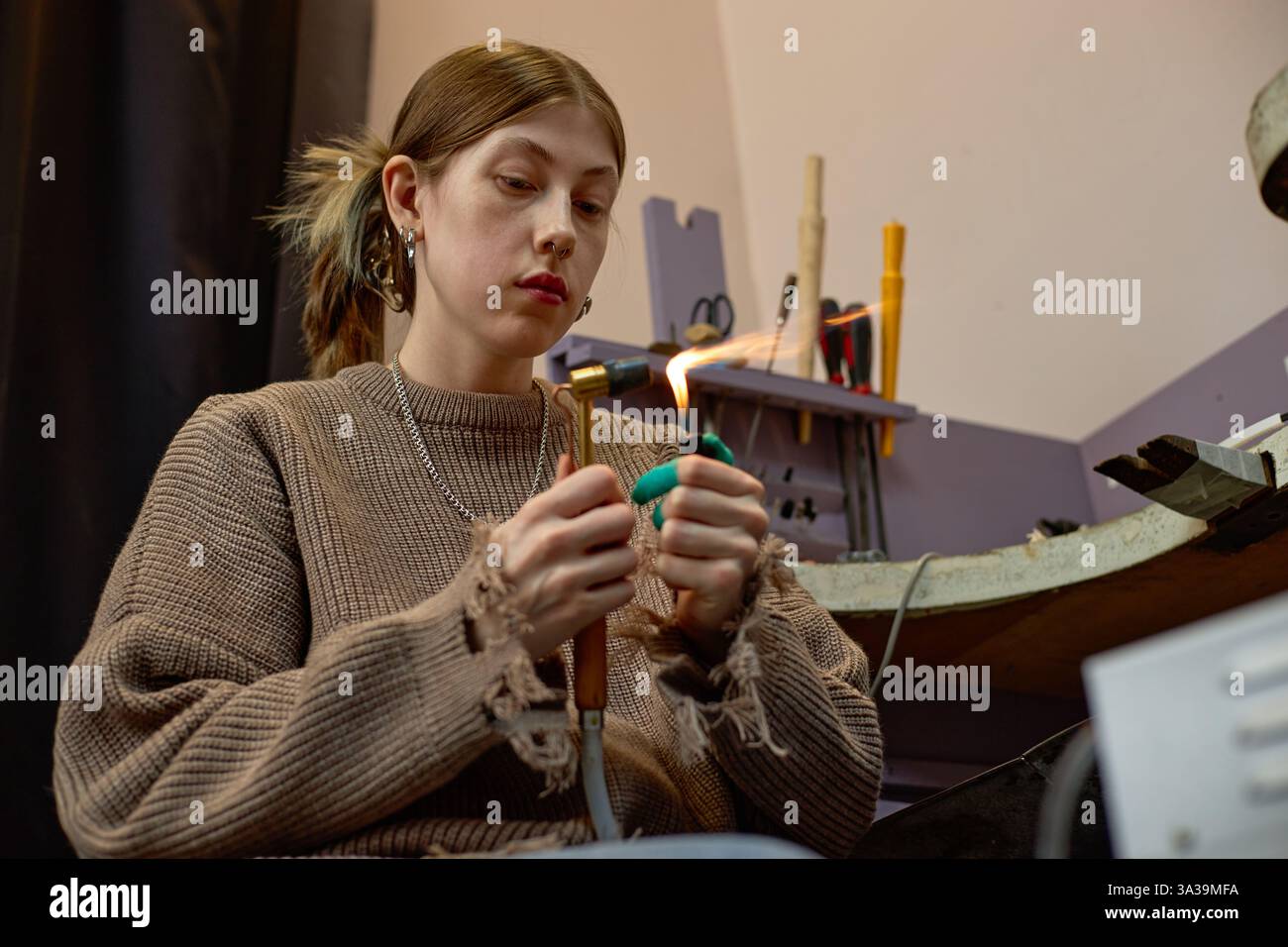 Young woman concentrating on engineering project in workshop, holding ...