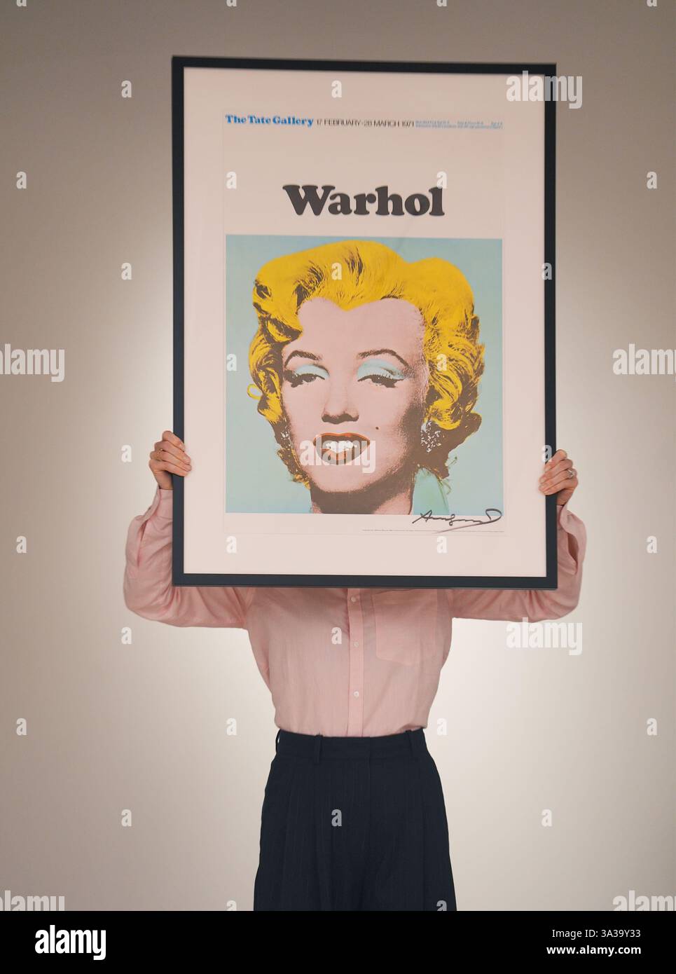 A member of gallery staff holding a signed Tate Gallery poster by Andy ...