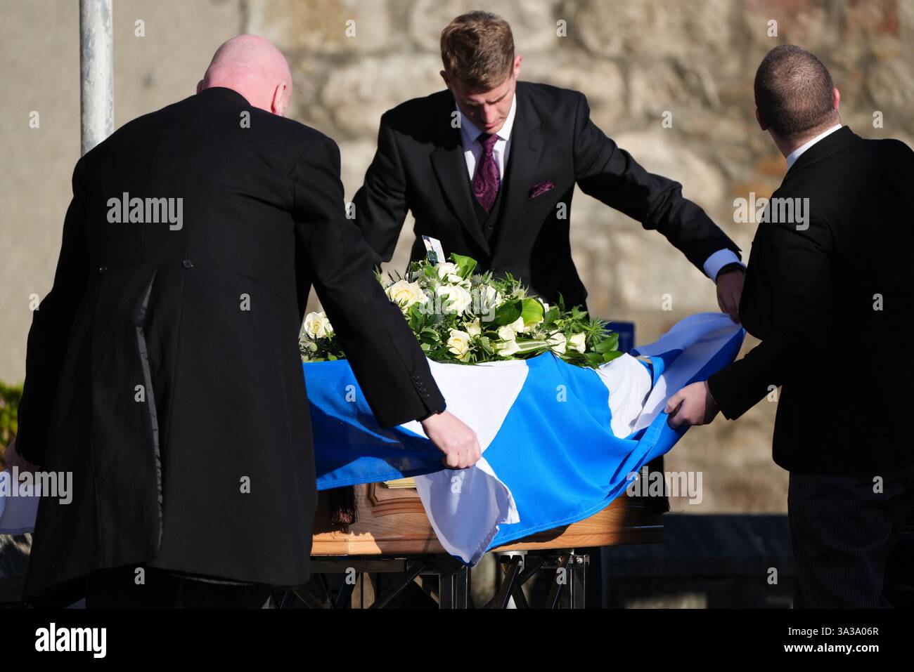 Pall bearers drape a Saltire flag over the coffin as it arrives at the ...