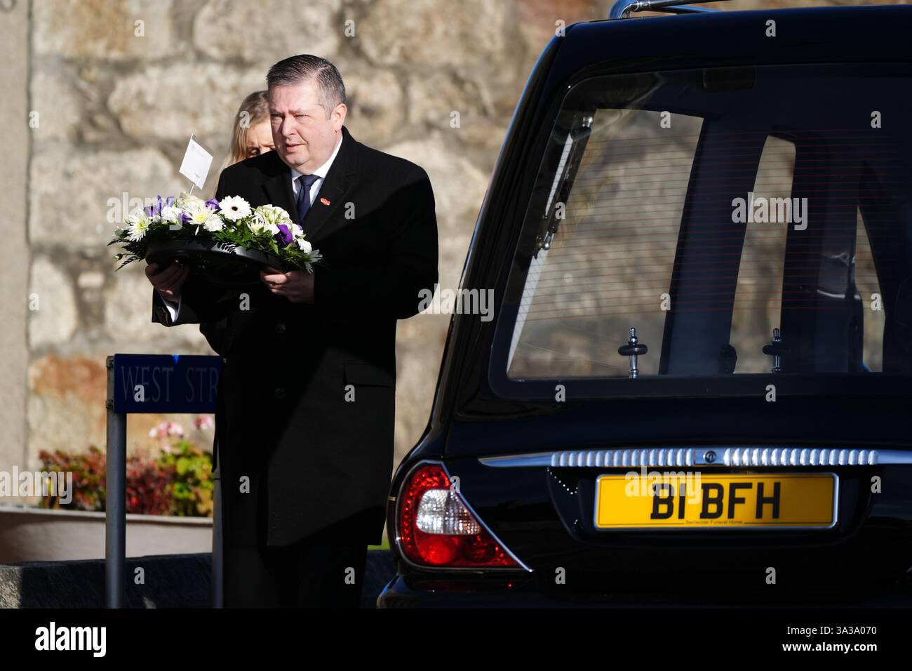 Lord Frank Mulholland carries a wreath as he arrives for the funeral ...