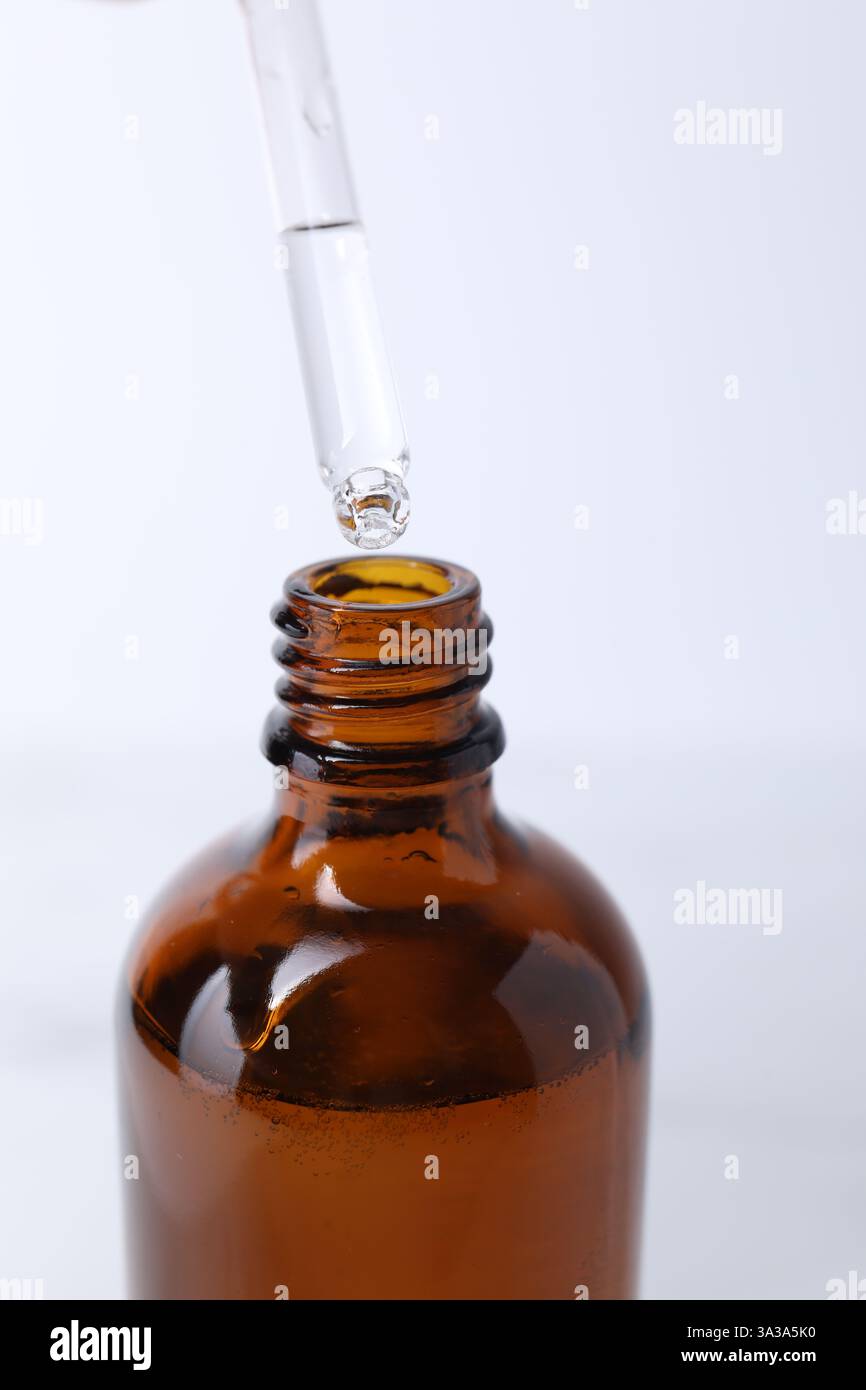 Dripping serum from pipette into bottle on light background, closeup ...