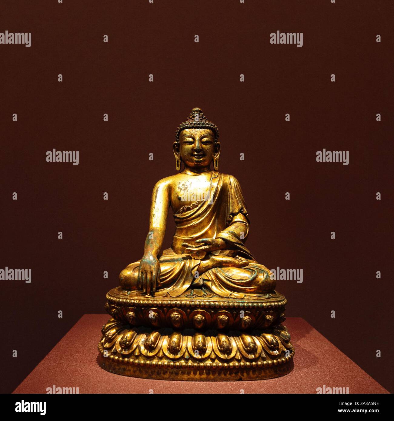 A museum exhibit of an antique Buddha sculpture in the lotus position ...
