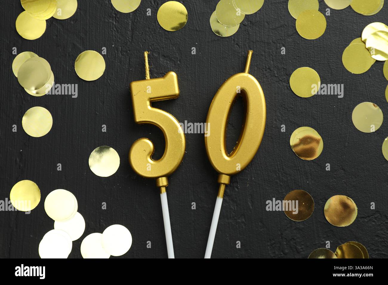 50th birthday. Number shaped candles and confetti on black background ...