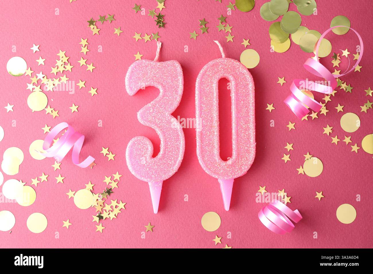 30th birthday. Number shaped candles and confetti on pink background ...