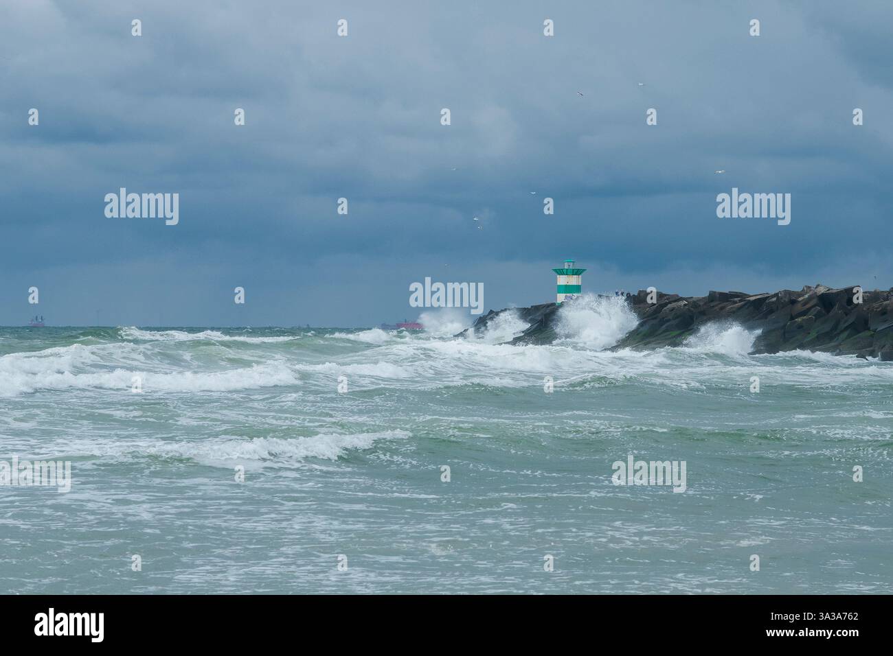 View on a pier and a lighthouse at the coast on a windy summer ...